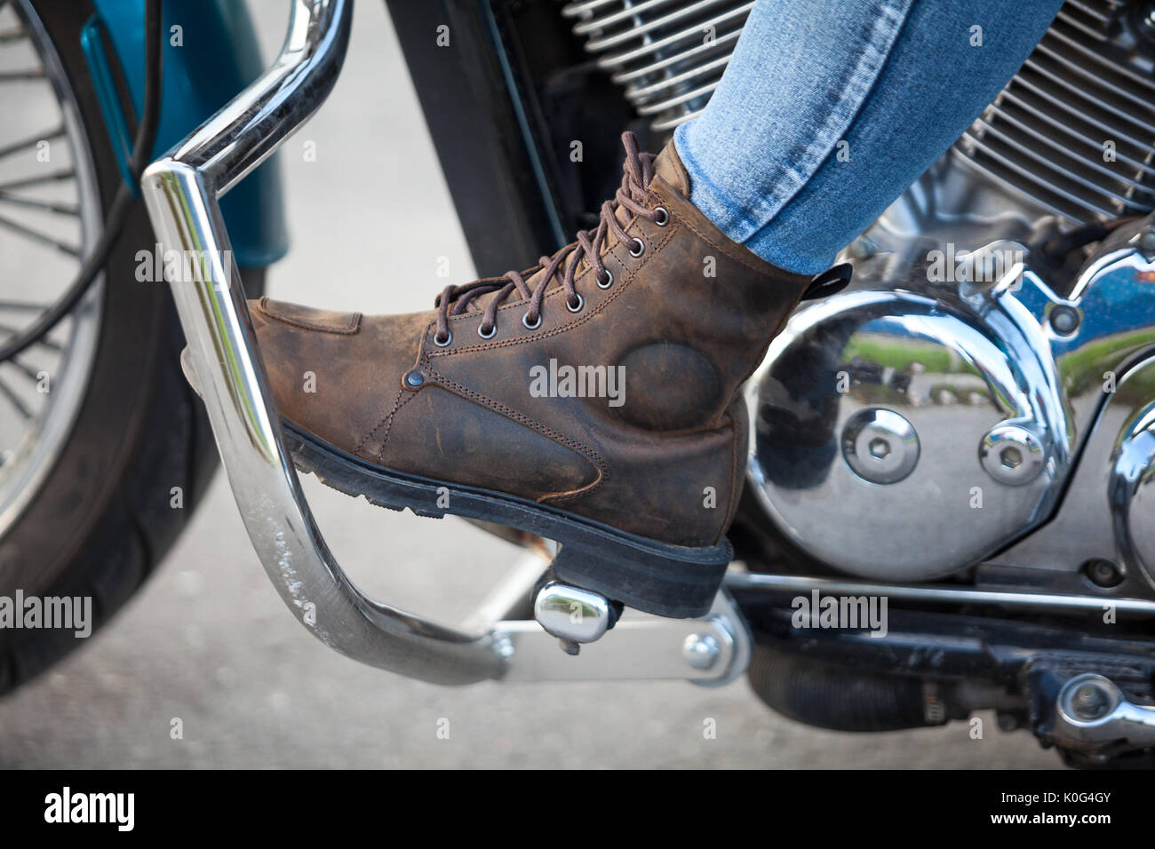 Side view at female foot with protective boot on the stands of chopper ...