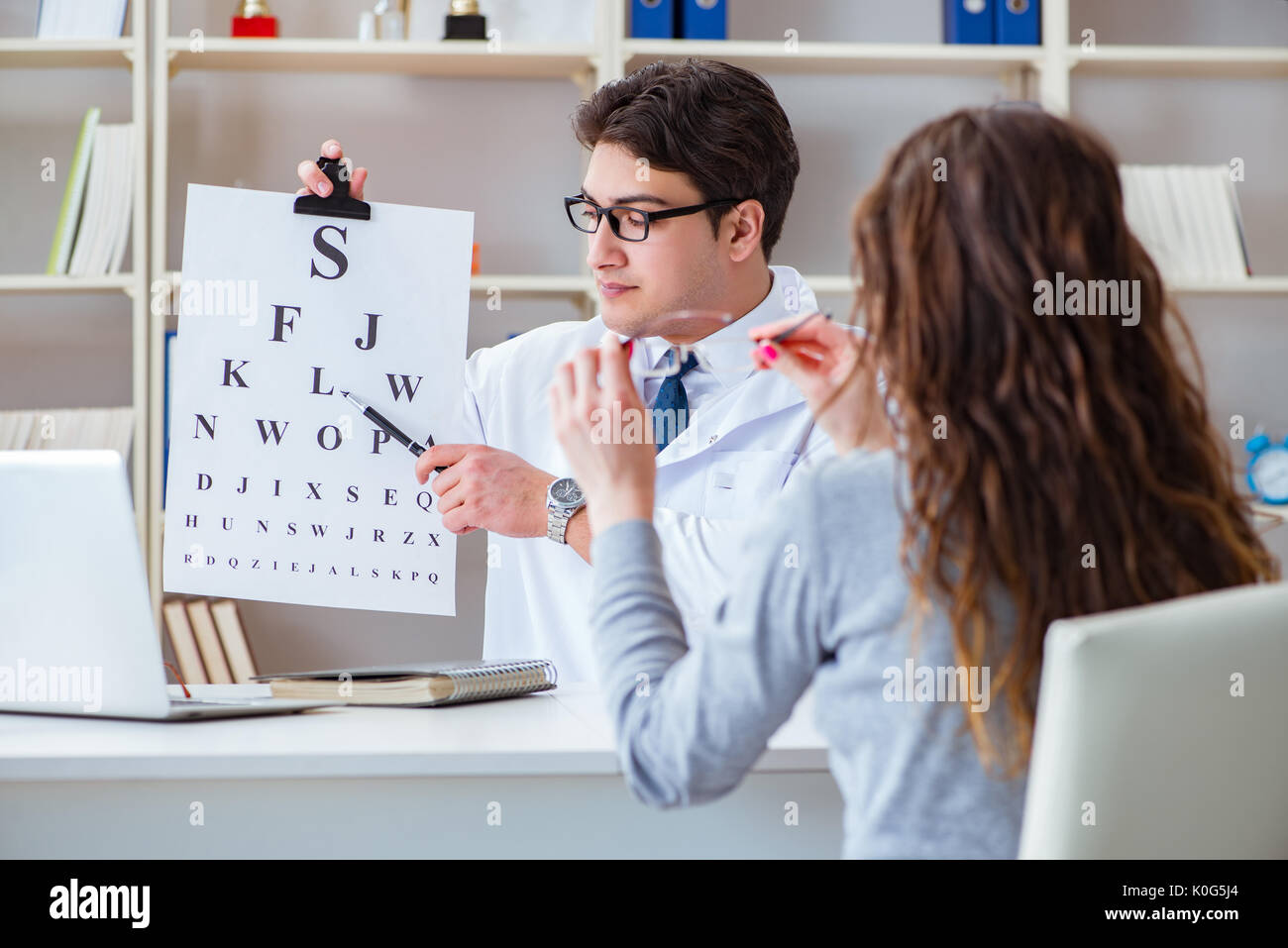 Doctor optician with letter chart conducting an eye test check Stock ...