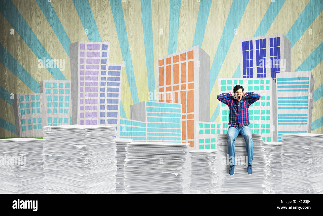 Young man sitting on pile of paper documents Stock Photo - Alamy