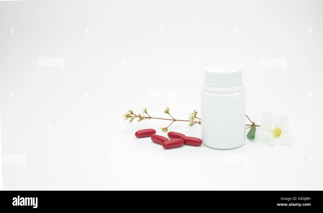 Red vitamin and supplement capsule pills with flower and branch with ...