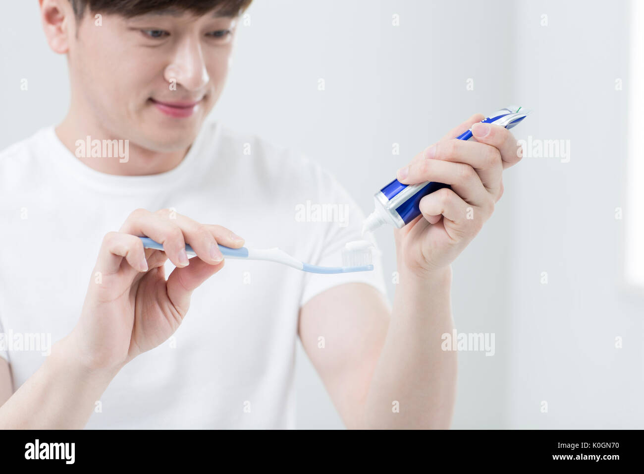Portrait of smiling man squeezing toothpaste on toothbrush Stock Photo ...