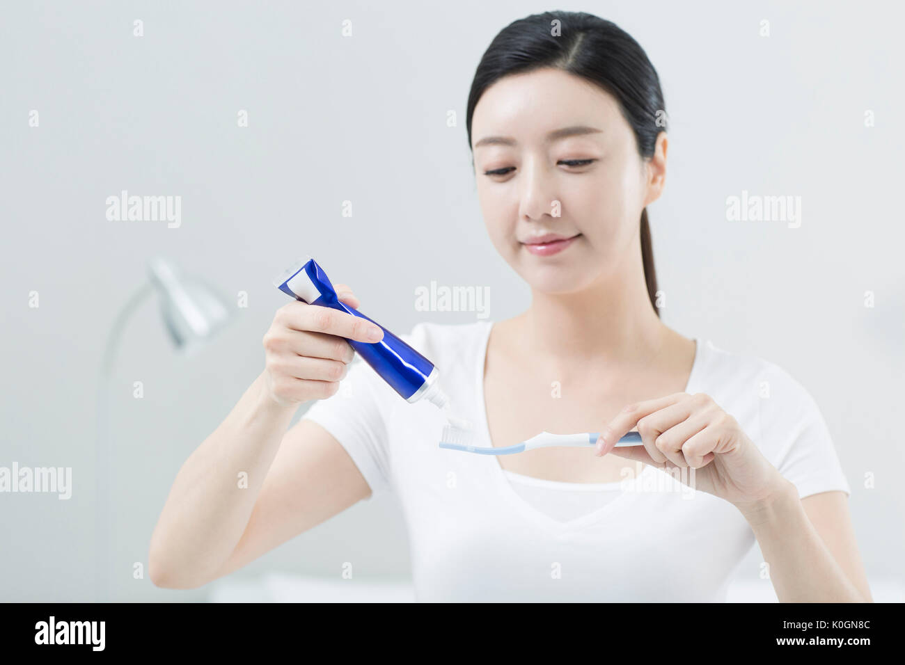 Portrait of smiling woman squeezing toothpaste on toothbrush Stock ...
