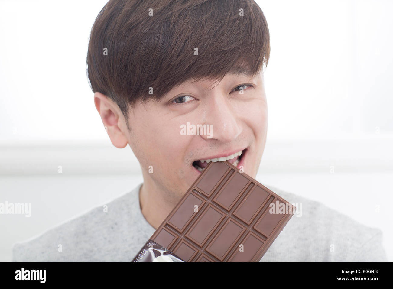 Portrait of smiling man eating chocolate Stock Photo - Alamy