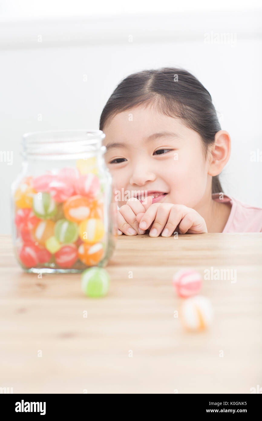 Portrait of smiling girl watching candies in a jar Stock Photo - Alamy