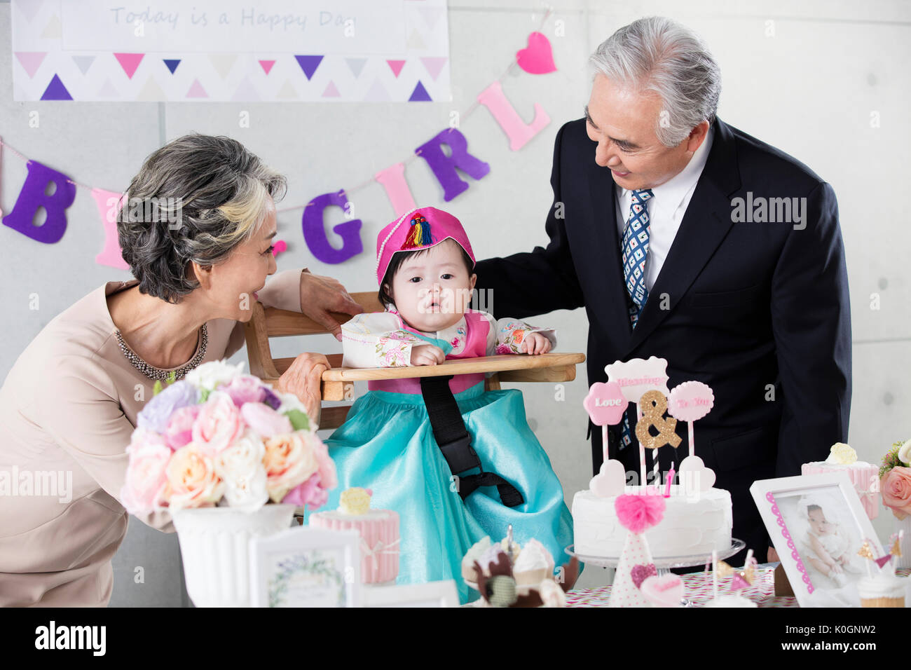 Portrait of loving grandparents and baby girl at first birthday party ...