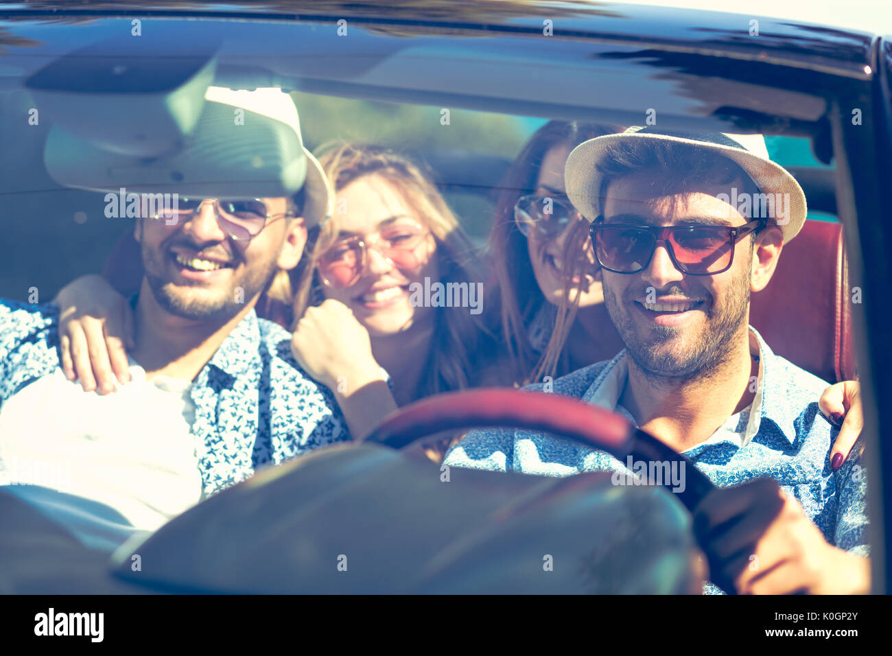 Group of cheerful young friends driving car and smiling in summer Stock ...