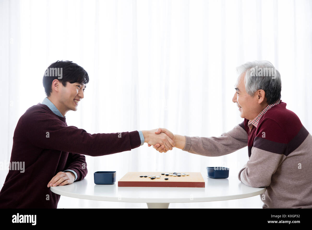 Side view of smiling senior man and young man making a handshake over ...