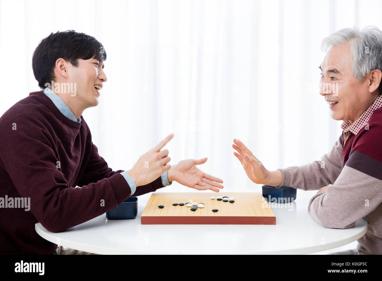 Side view of young smiling man and his senior father playing go Stock ...