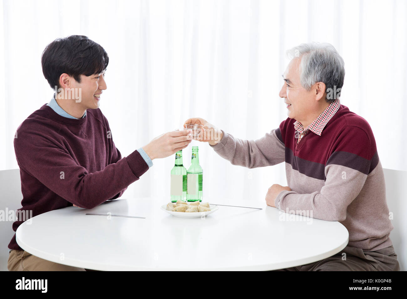 Side view of smiling son and his senior father drinking Stock Photo - Alamy