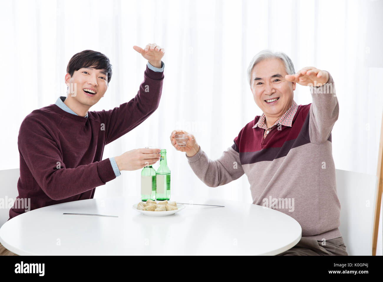 Smiling young son and his senior father drinking Stock Photo - Alamy