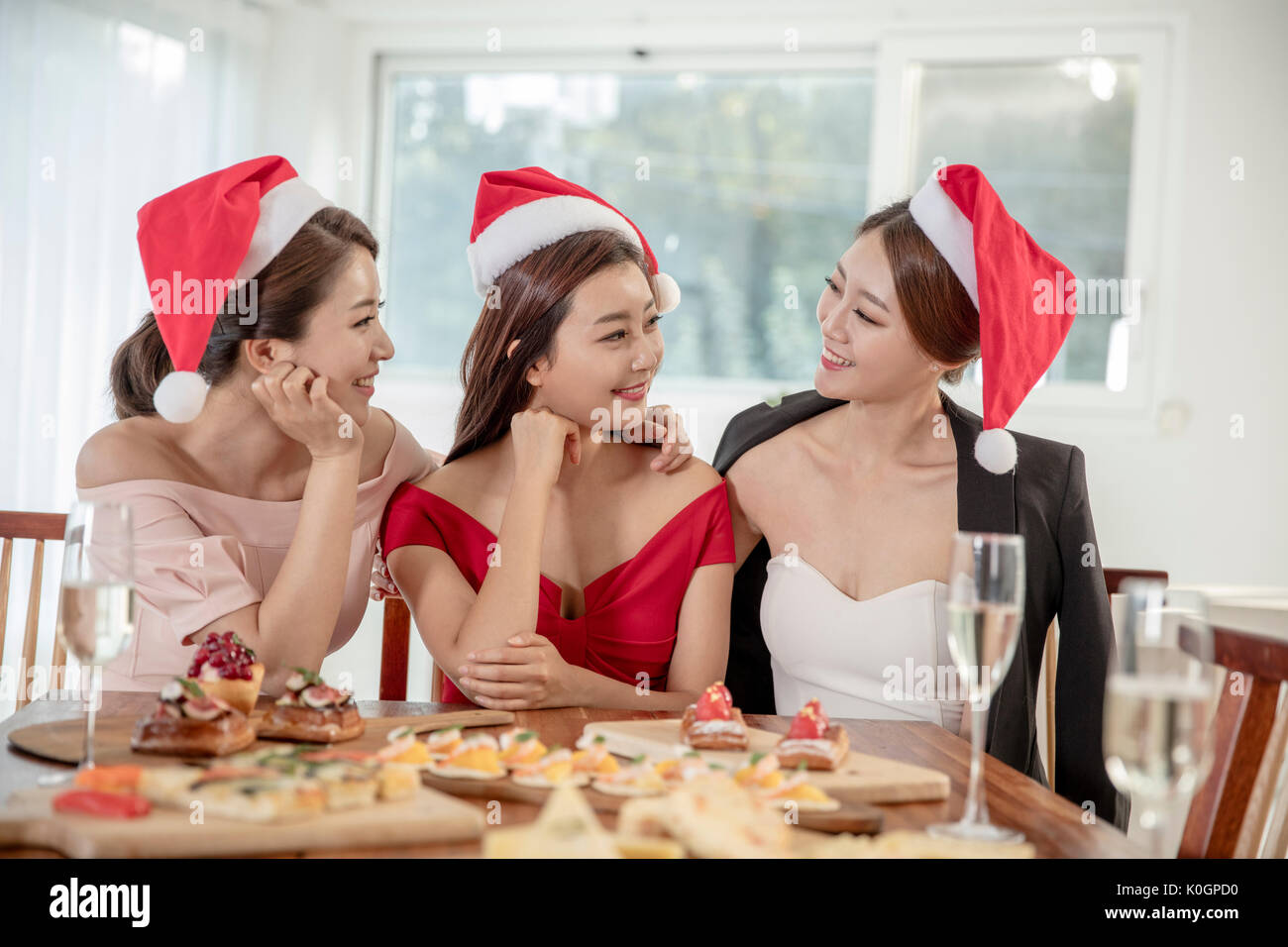 Three young smiling women having Christmas party Stock Photo - Alamy