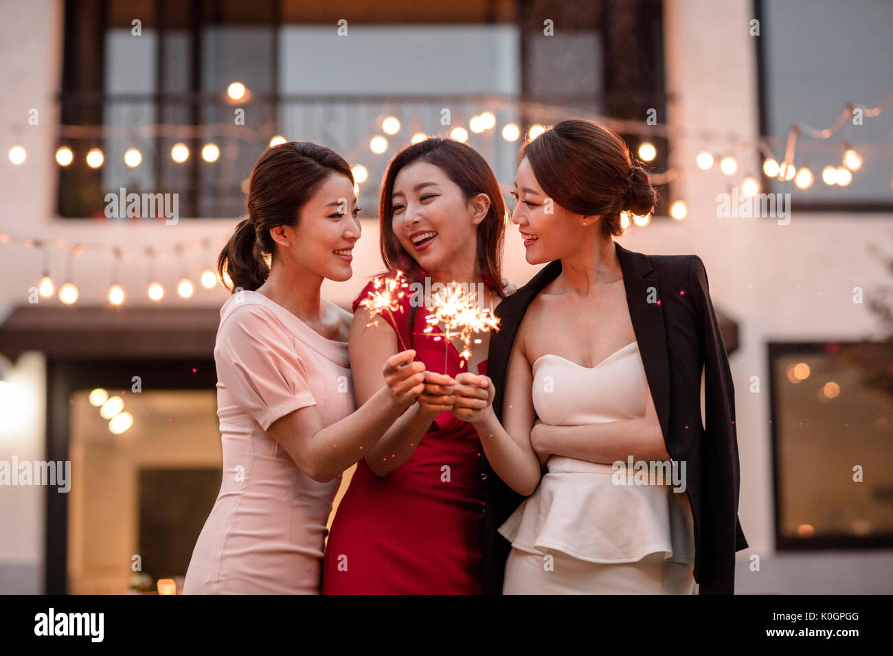 Three young smiling women with firecrackers enjoying a party outdoors ...