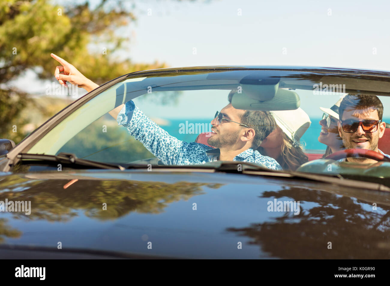 Group of cheerful young friends driving car and smiling in summer Stock ...