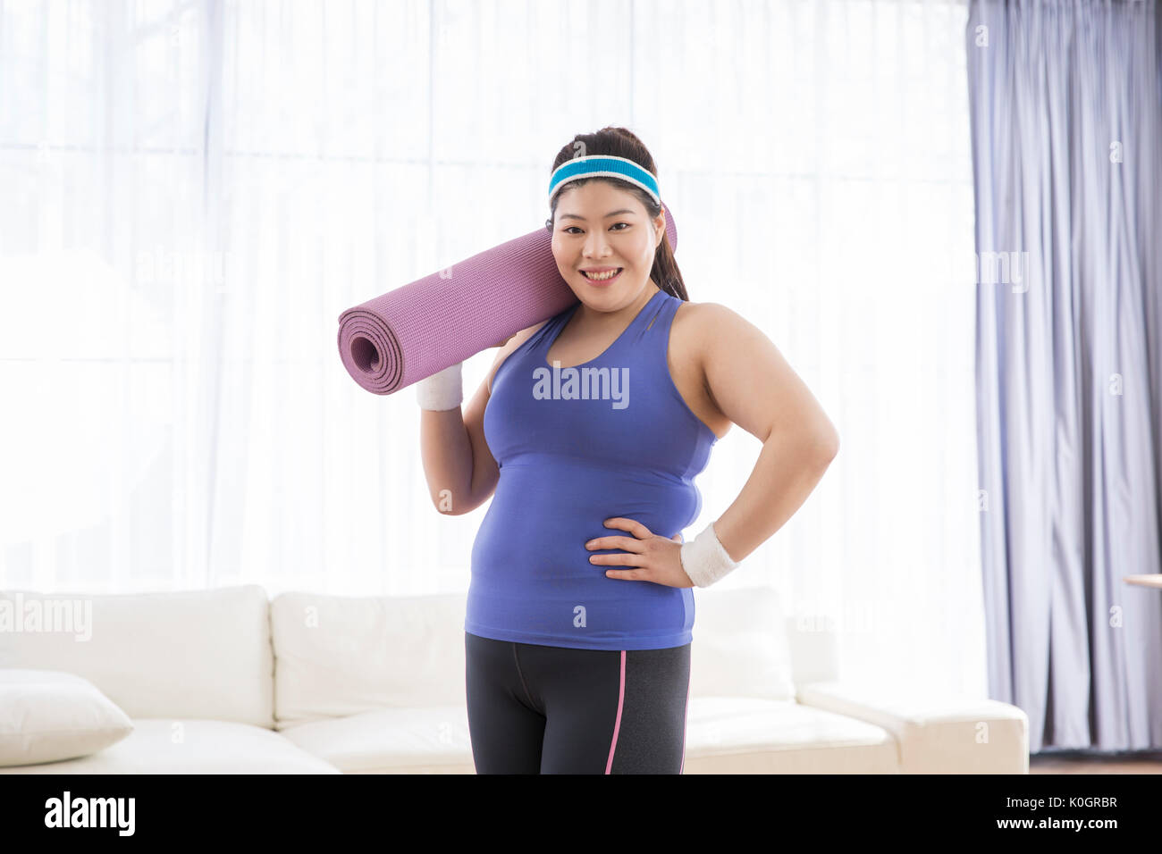 Young smiling fat woman with a roll of mat posing Stock Photo - Alamy