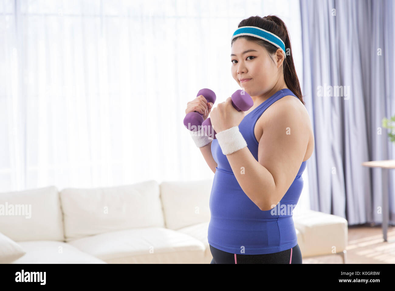 Side view of young fat woman with dumbbells posing Stock Photo - Alamy