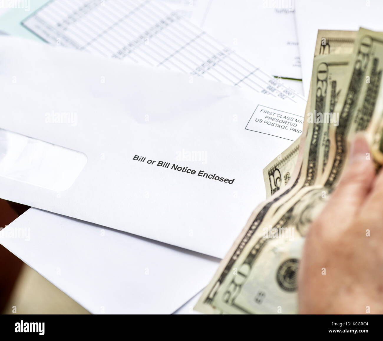 Stack of bills due with a hand holding US currency with shallow depth ...