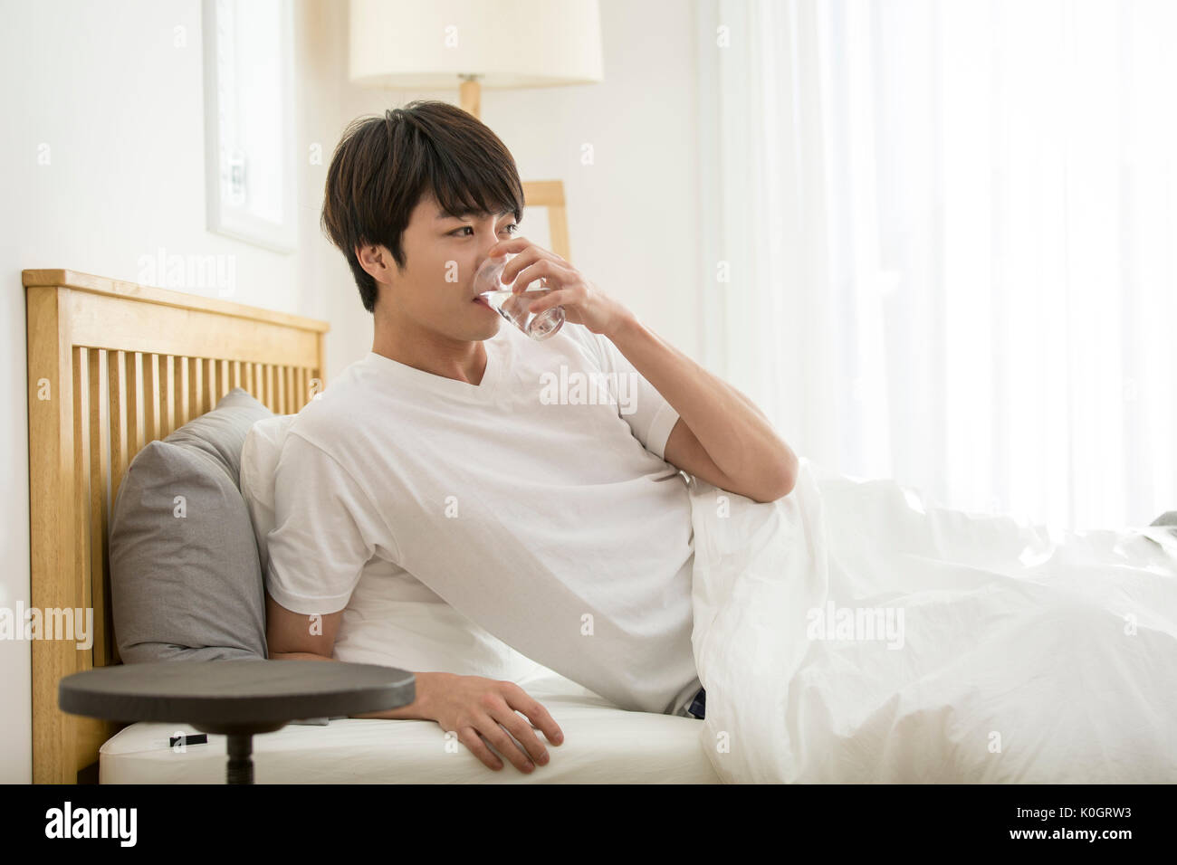 Single man drinking water in bed Stock Photo - Alamy