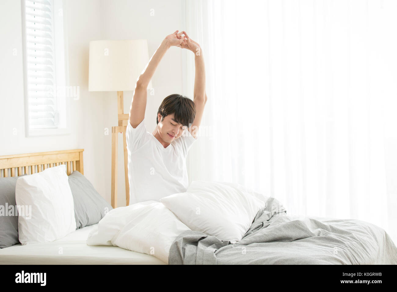Single man stretching his arms in bed Stock Photo - Alamy