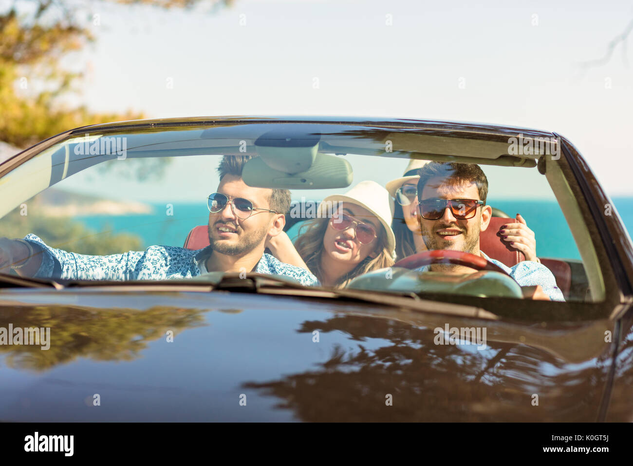 Group of cheerful young friends driving car and smiling in summer Stock ...