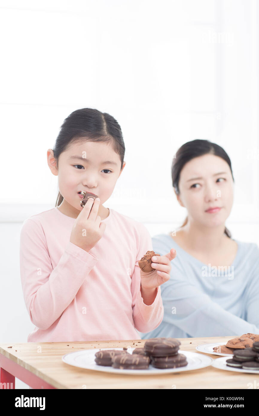 Girl eating sweets and her mother worried Stock Photo - Alamy