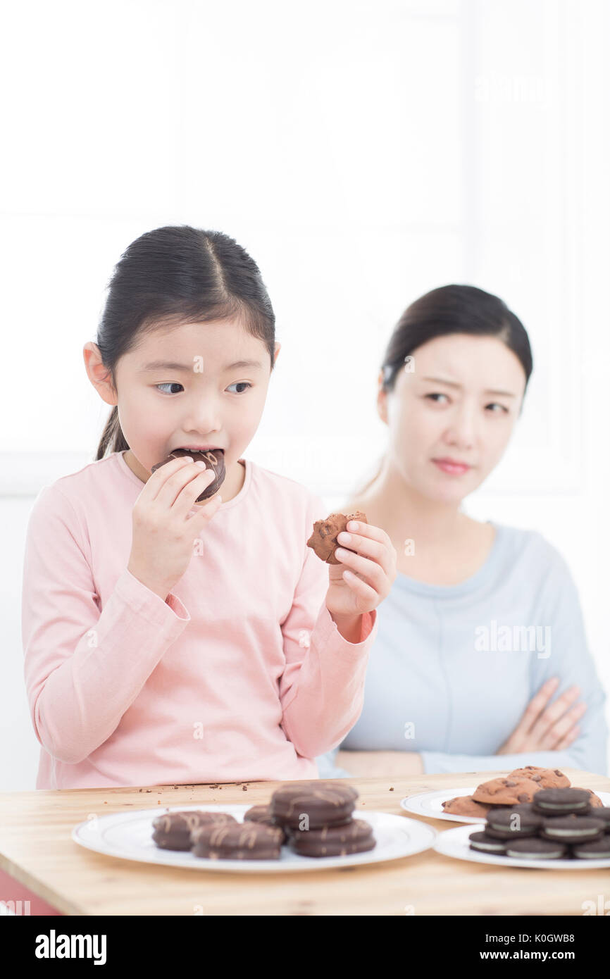 Girl eating sweets and her mother worried Stock Photo - Alamy