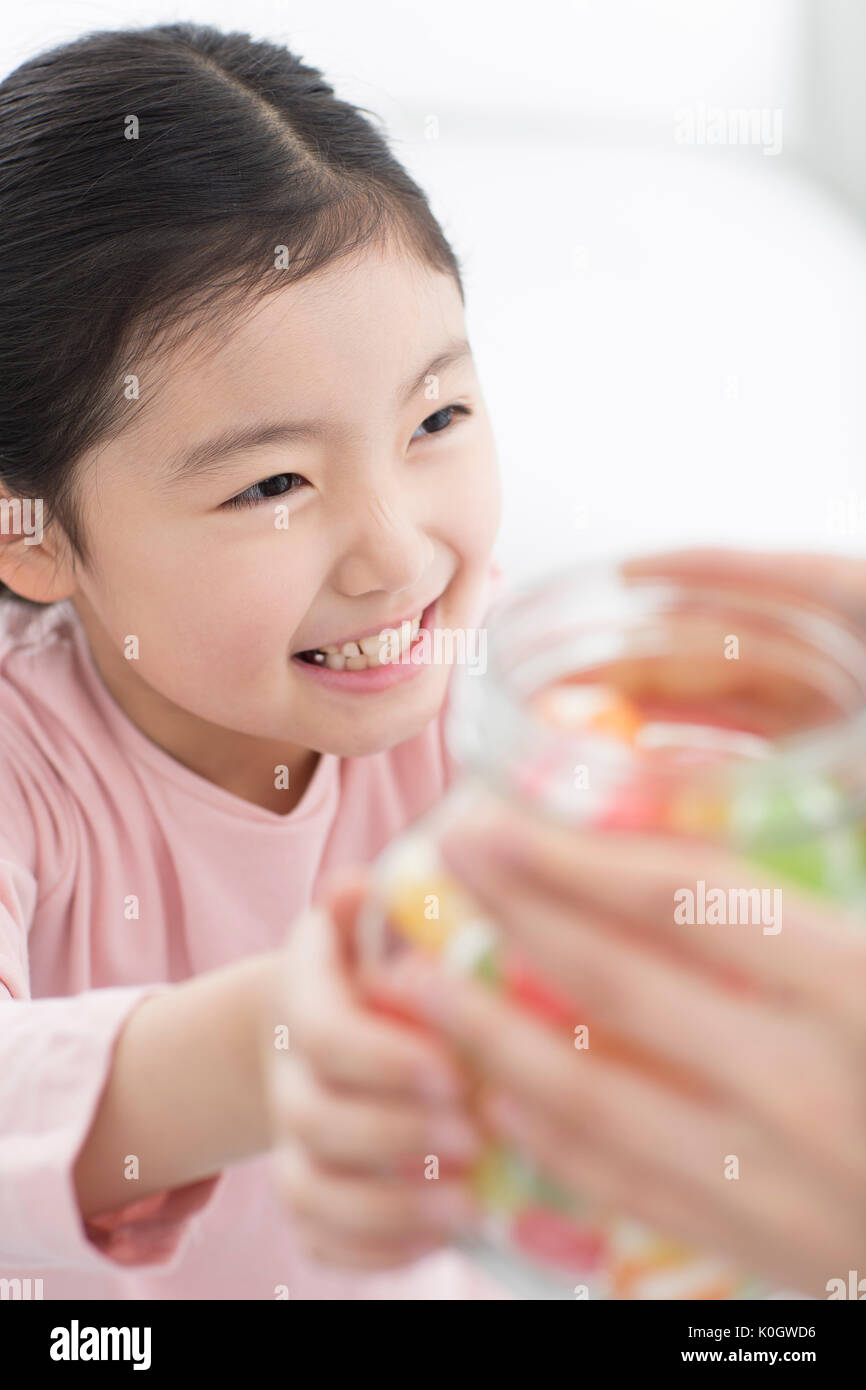 Portrait of smiling girl taking a jar of candy Stock Photo - Alamy