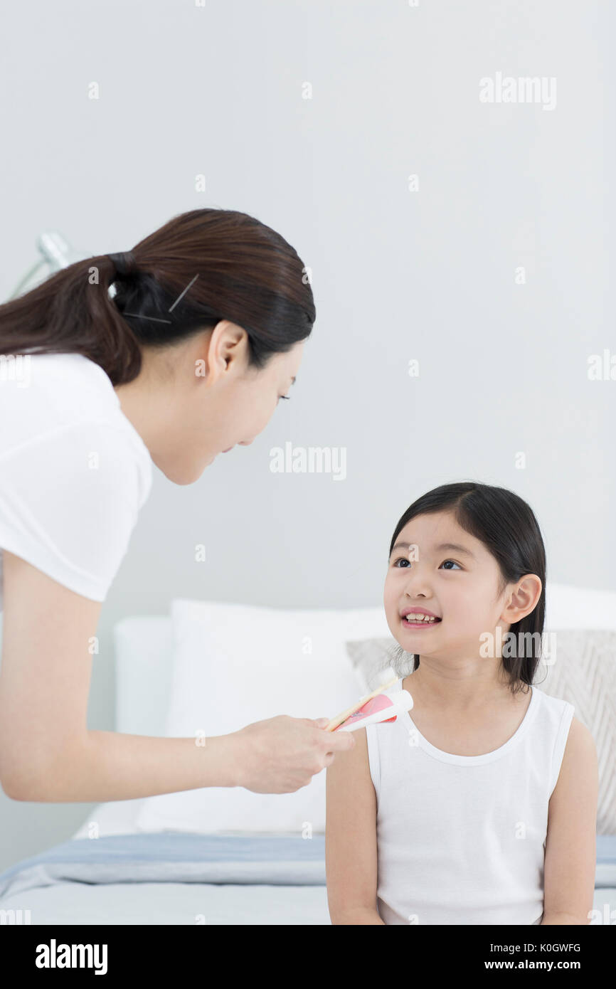 Smiling mother giving toothpaste and toothbrush to her daughter Stock ...