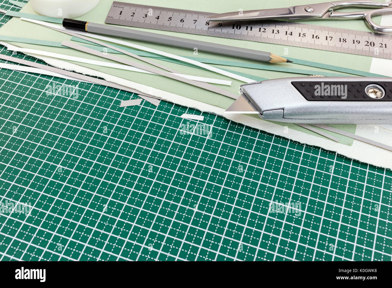 green cutting mat with various office or school stationery and tools ...