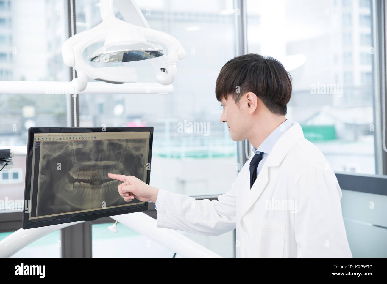Side view portrait of dentist pointing at an x-ray picture on computer ...