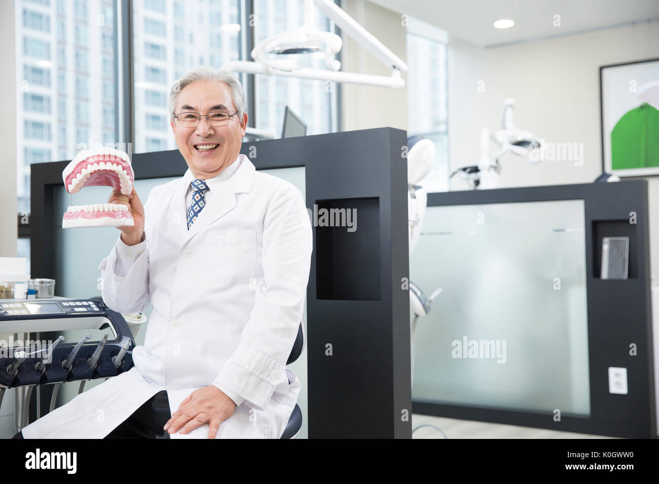 Smiling dentist showing model teeth Stock Photo - Alamy