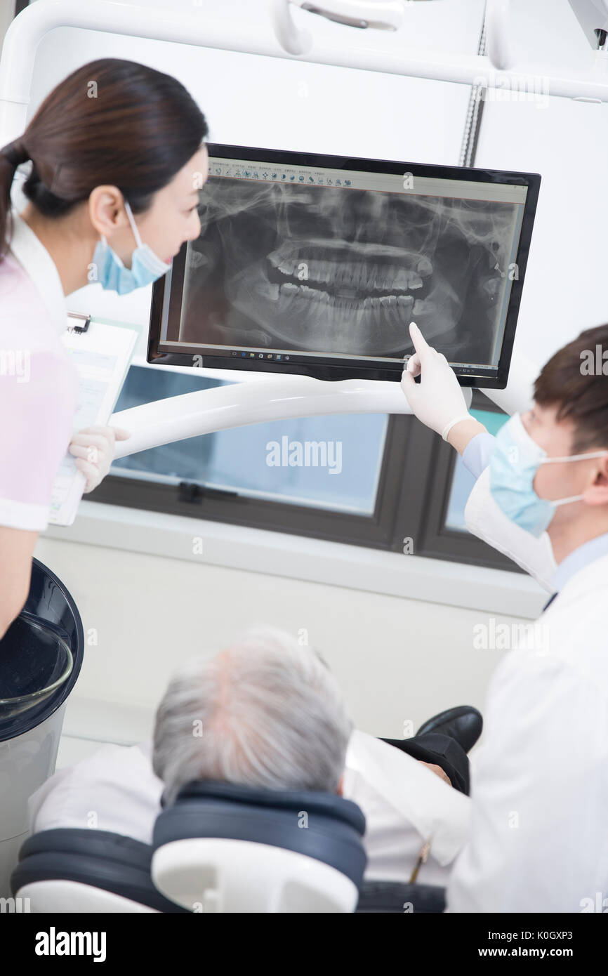 Dentist and dental hygienist showing an x-ray picture to a senior male ...