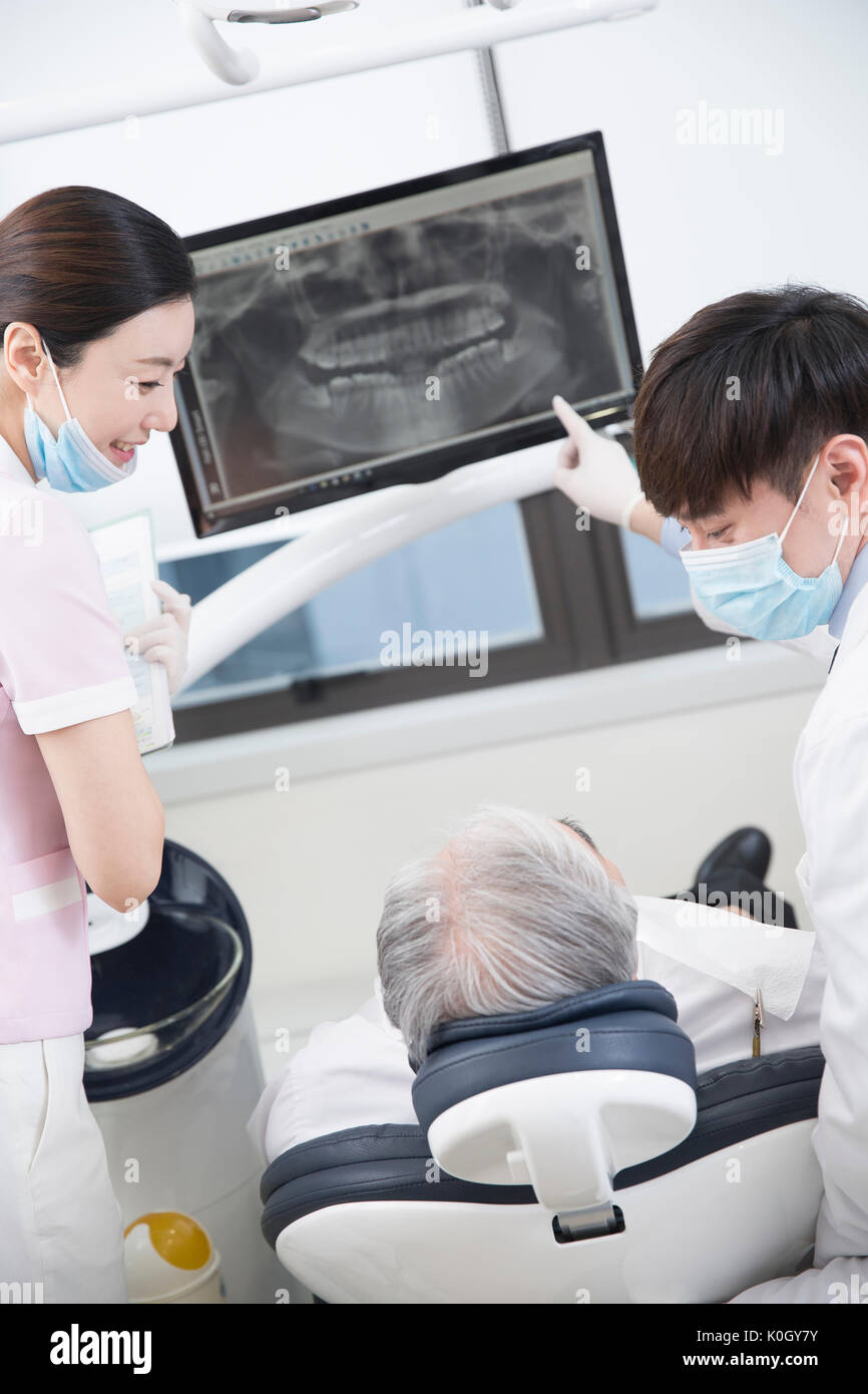 Smiling dental hygienist and dentist showing an x-ray picture to a ...