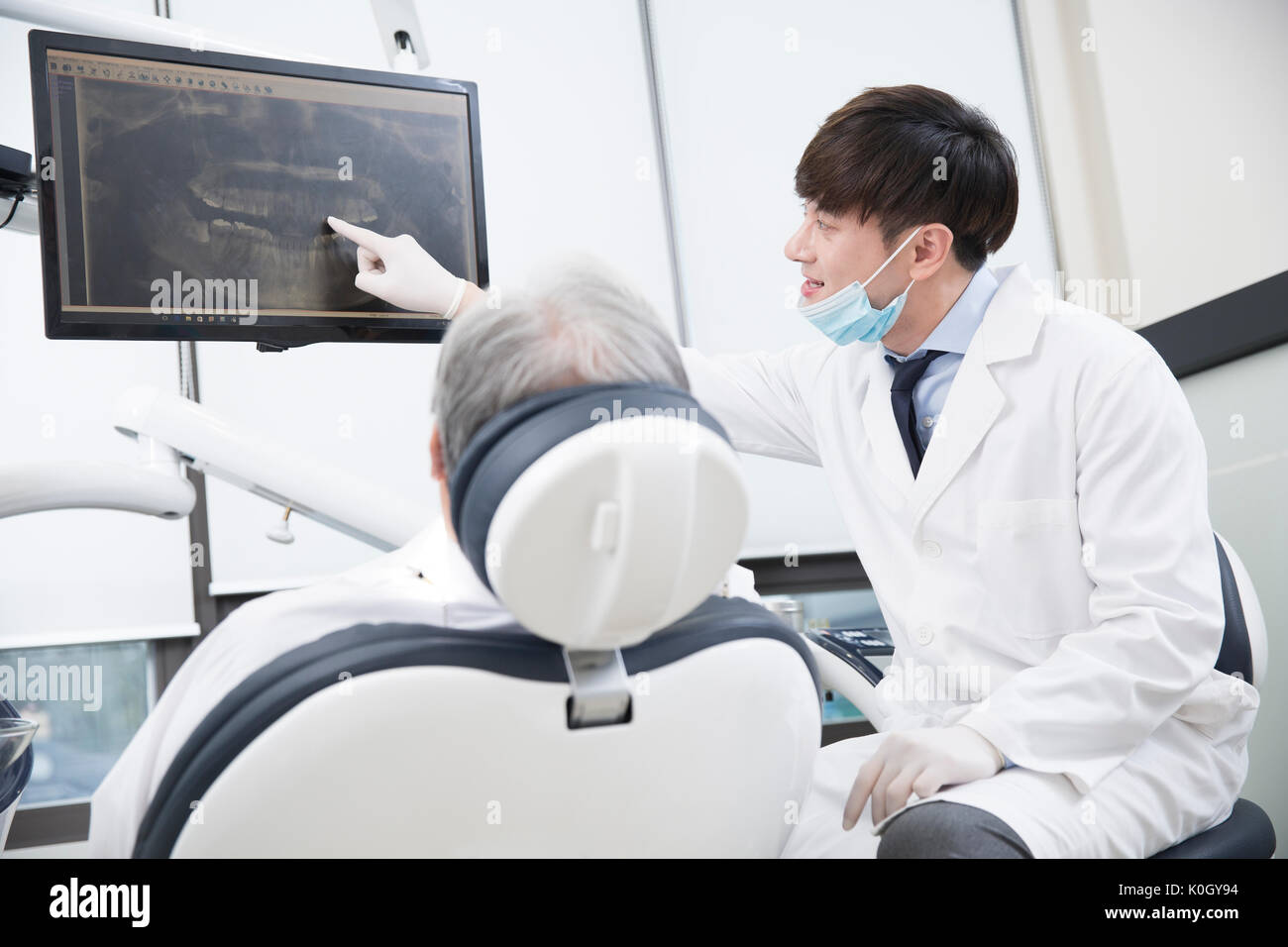 Smiling dentist showing an x-ray picture of teeth to a senior male ...
