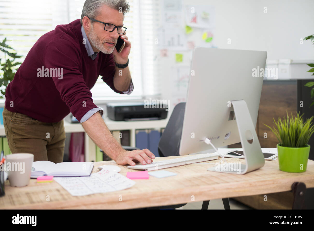 Busy man using telephone and computer simultaneously Stock Photo - Alamy