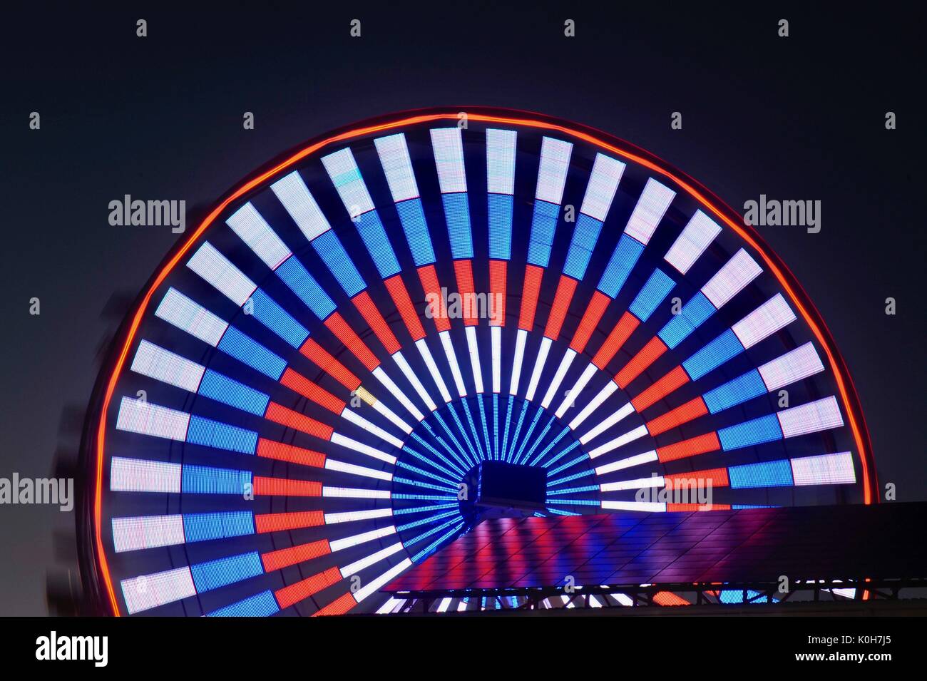 Spectacularly colorful, LED-lit ferris wheel spinning at night, with ...