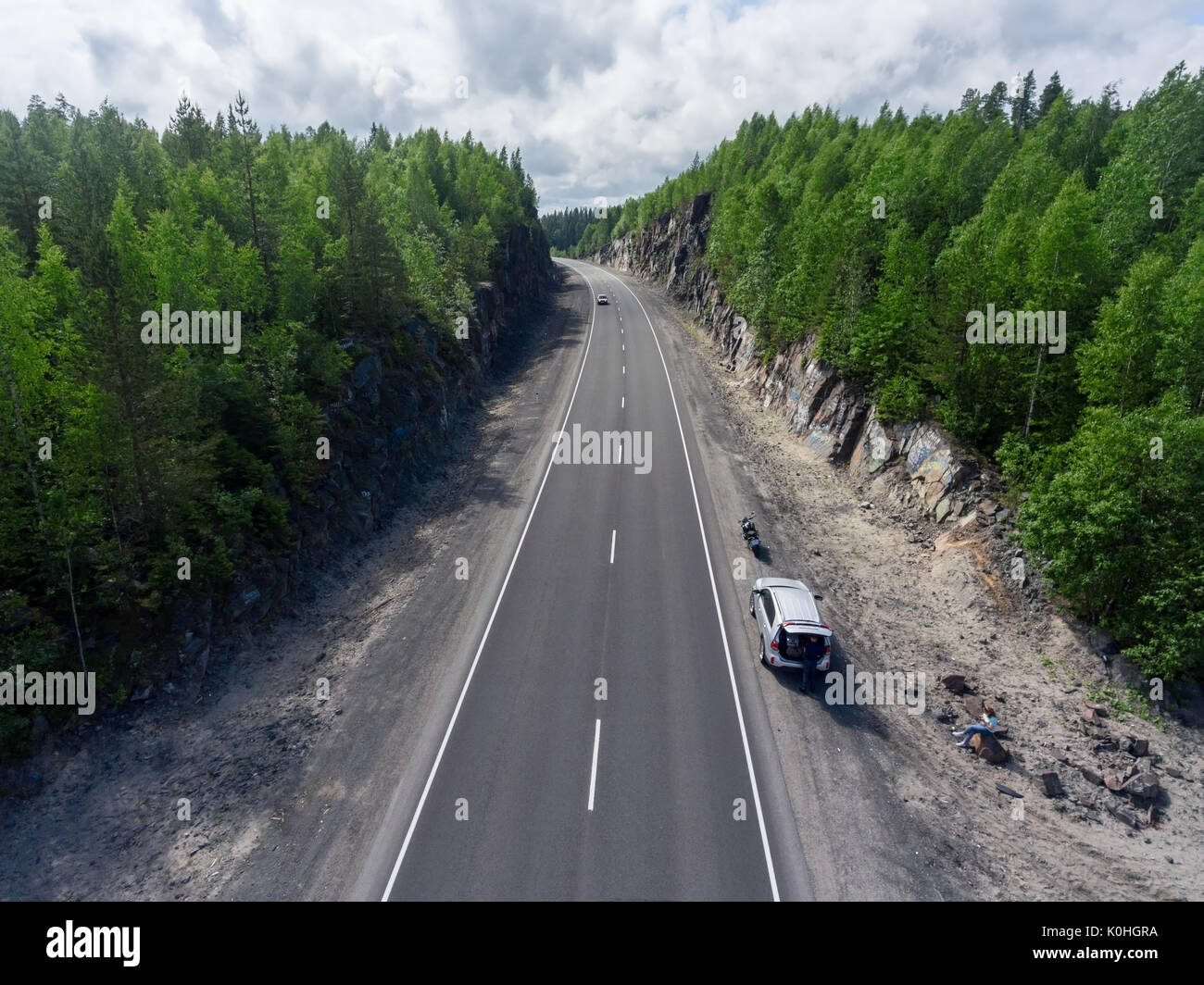 Passenger car and motorcycle standing on roadside of country two lane ...