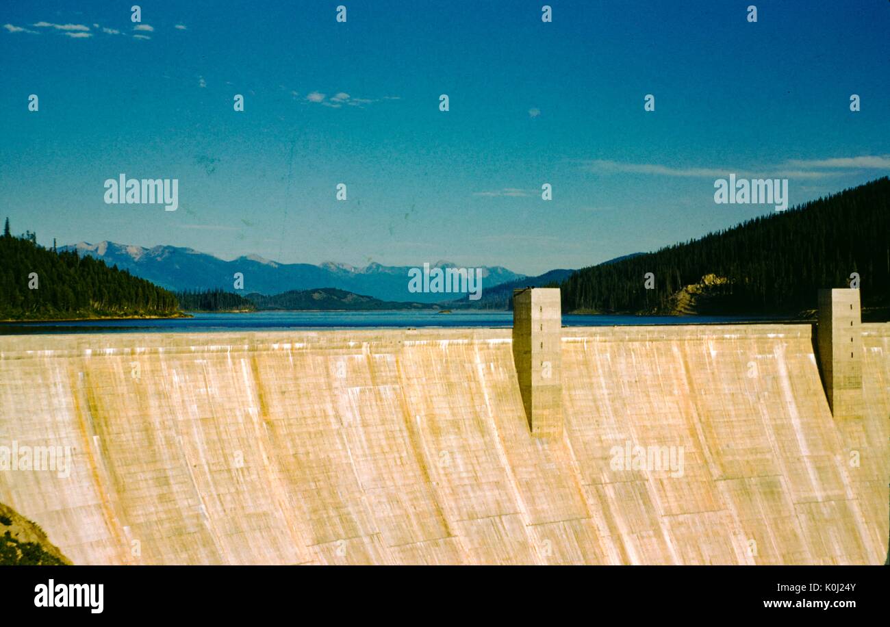 A large dam blocks the flow of a river that is surrounded by a ...