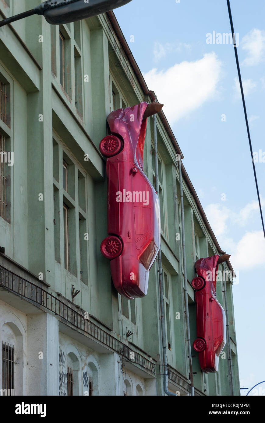 Two red cars hanging on the MeetFactory by artist David Černý, Prague ...
