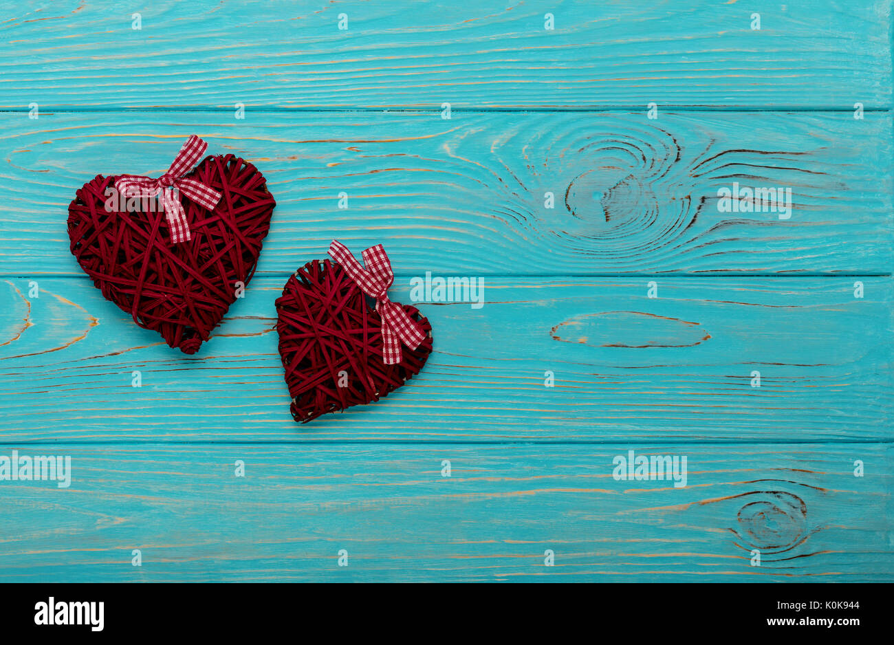Valentine's Day. Decorative wicker hearts of burgundy color on azure wood background. Selective ...