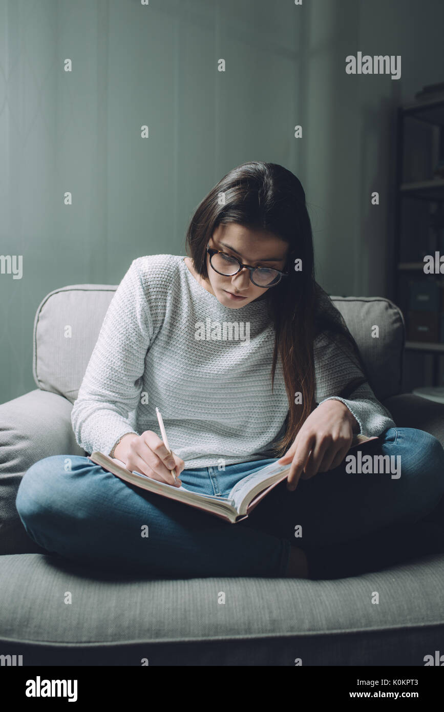 Girl studying the night before the exam, she is reading a book and ...