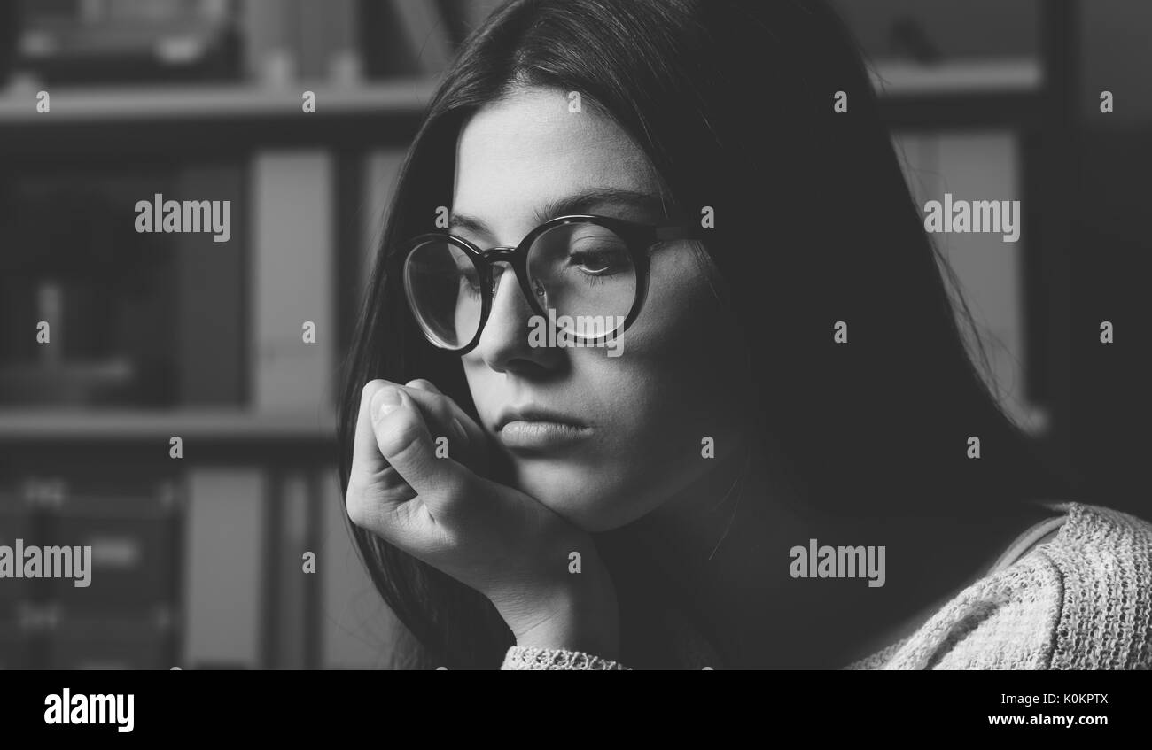Sad young woman posing with hand on chin, she is depressed and pensive ...