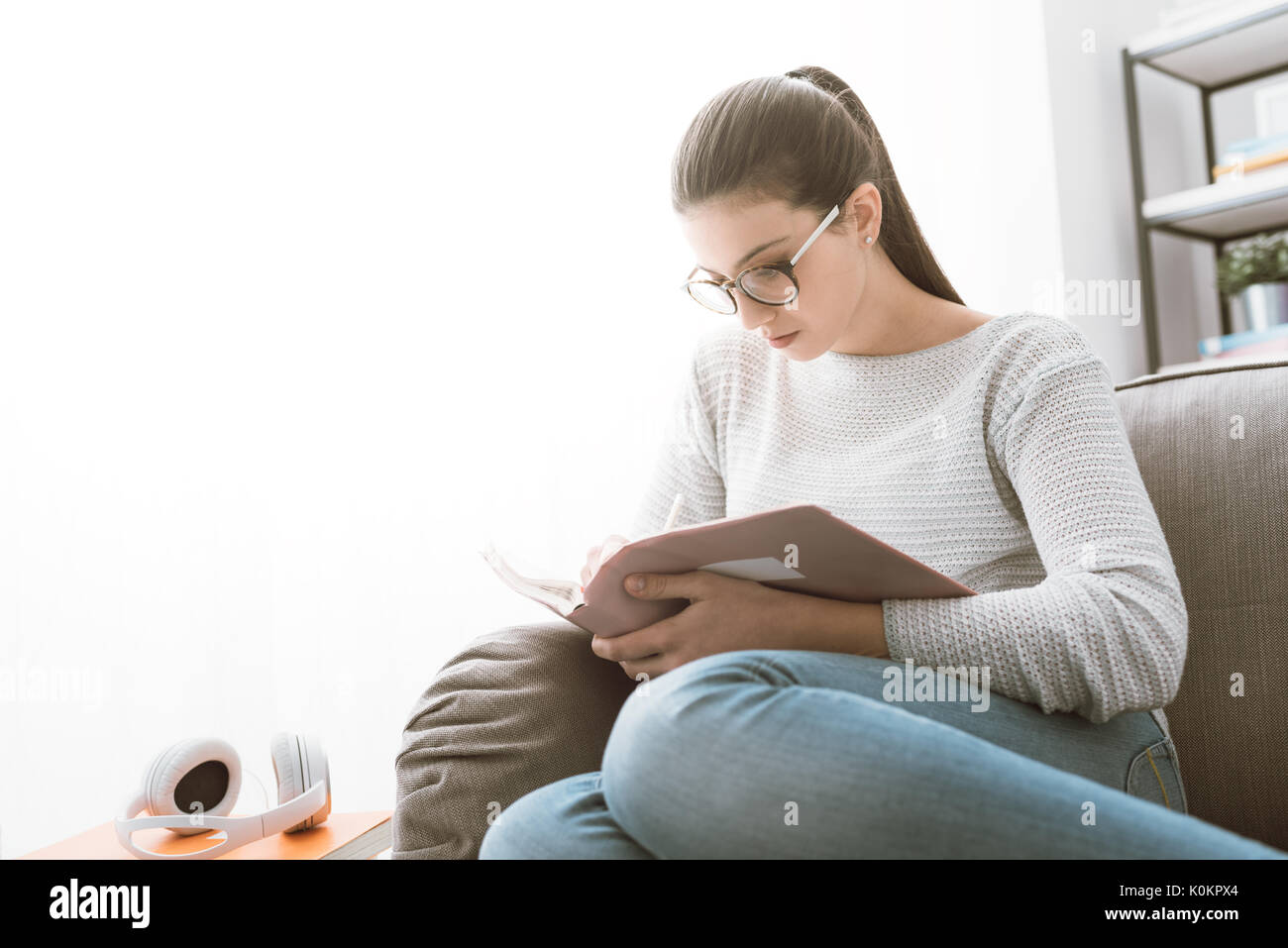 Smart female student doing homework, she is reading a book and holding ...