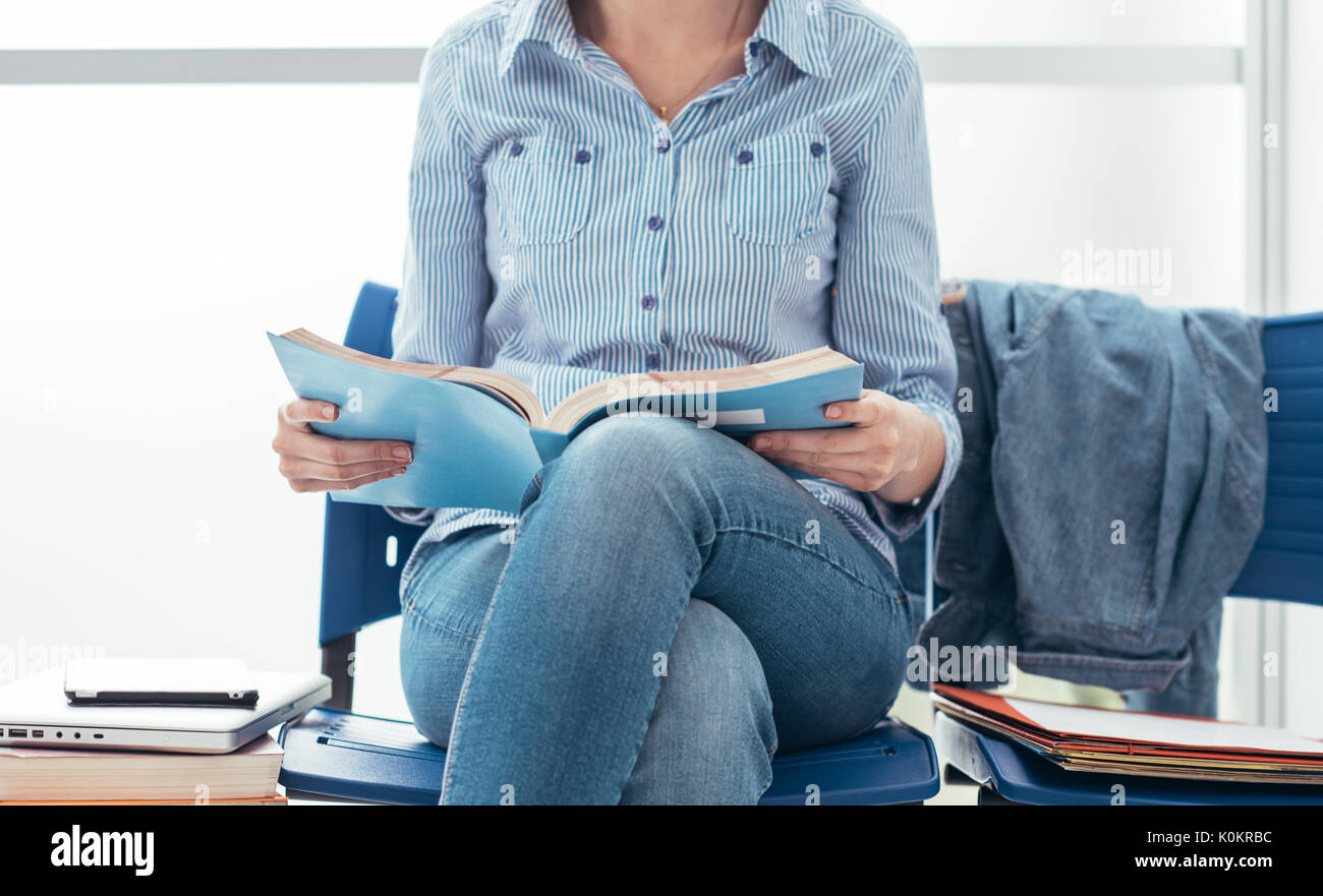 Young student in the waiting room, she is reviewing and preparing ...