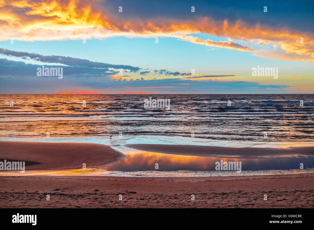 Beautiful sunset reflecting in low tide puddles at empty ocean beach ...
