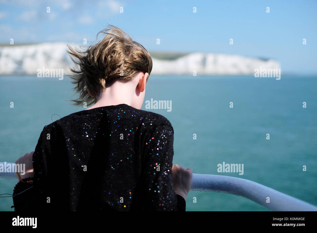 A young girl looks overboard on the ferry with the White Cliffs of ...