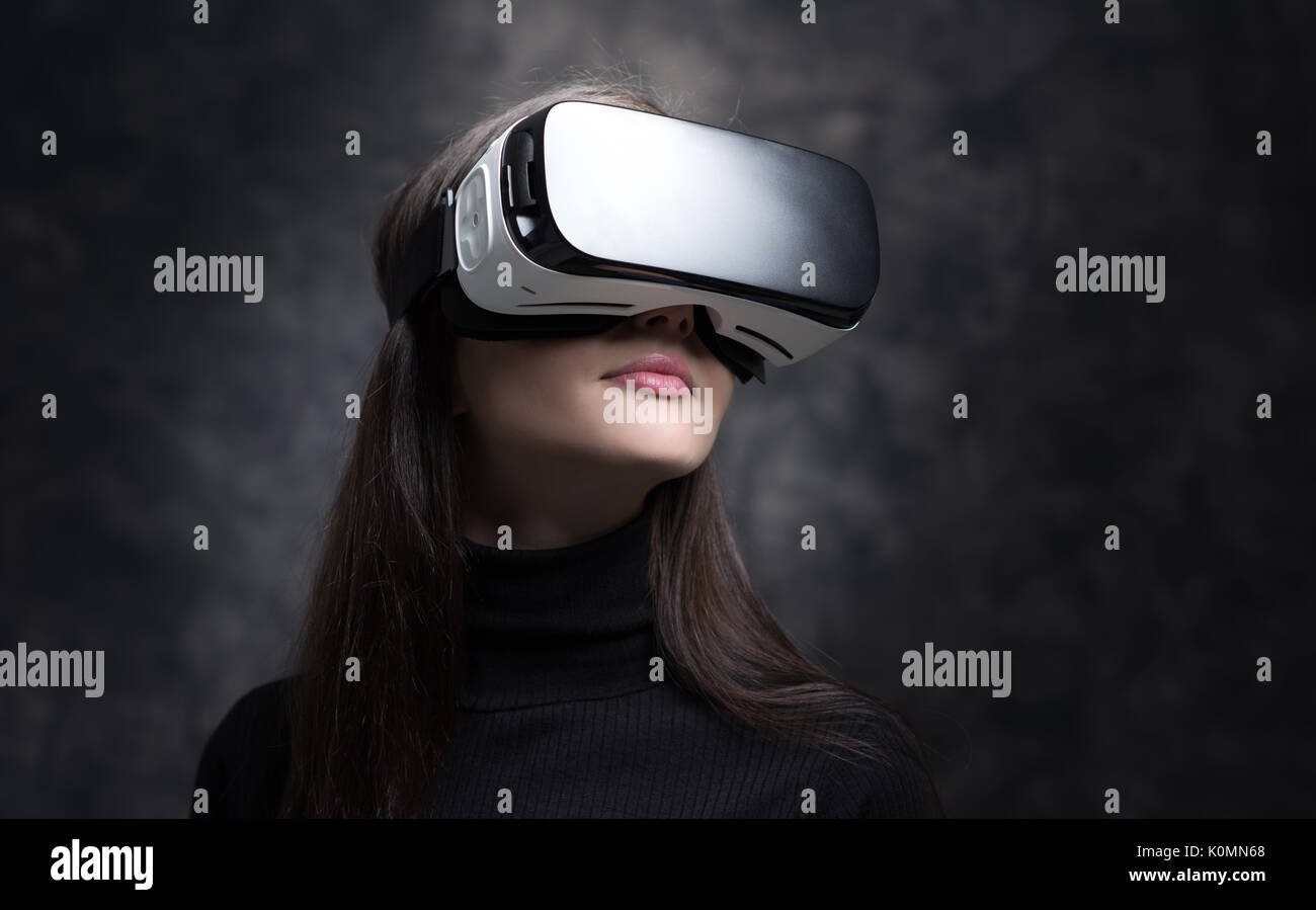 Young woman wearing VR glasses and interacting with virtual reality, entertainment and ...