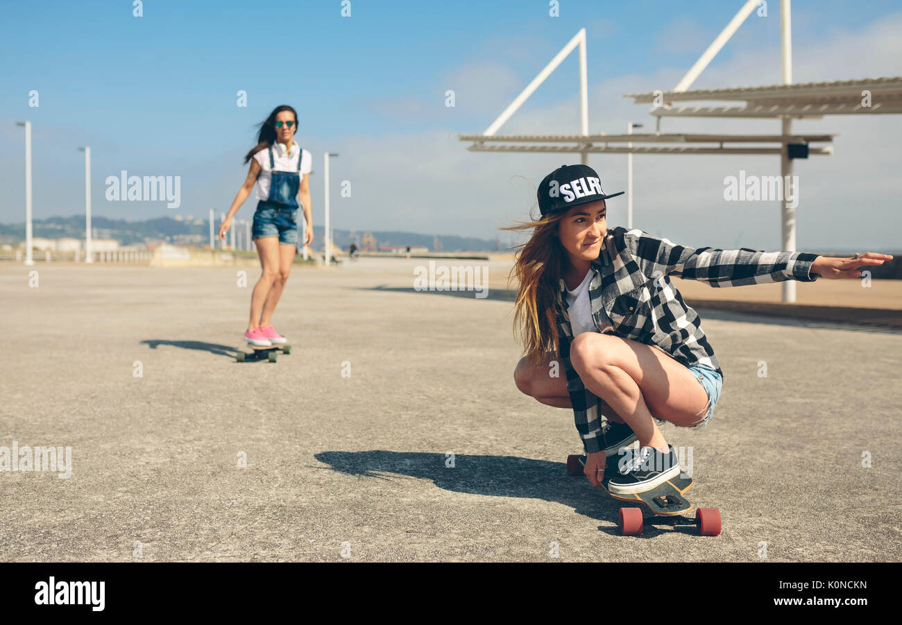 Two young women longboarding on beach promenade Stock Photo - Alamy