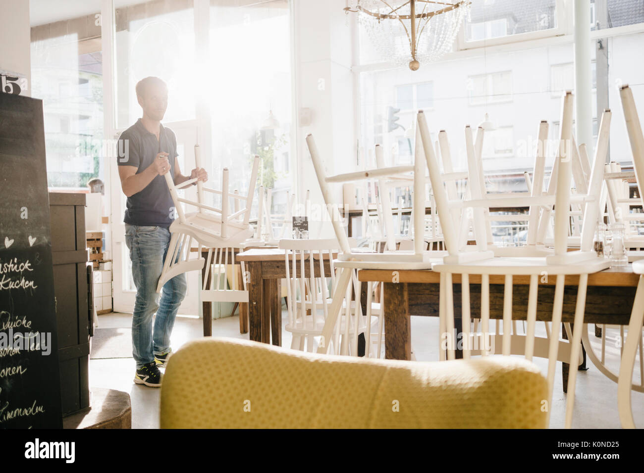 Man clearing cafe at closing time Stock Photo - Alamy