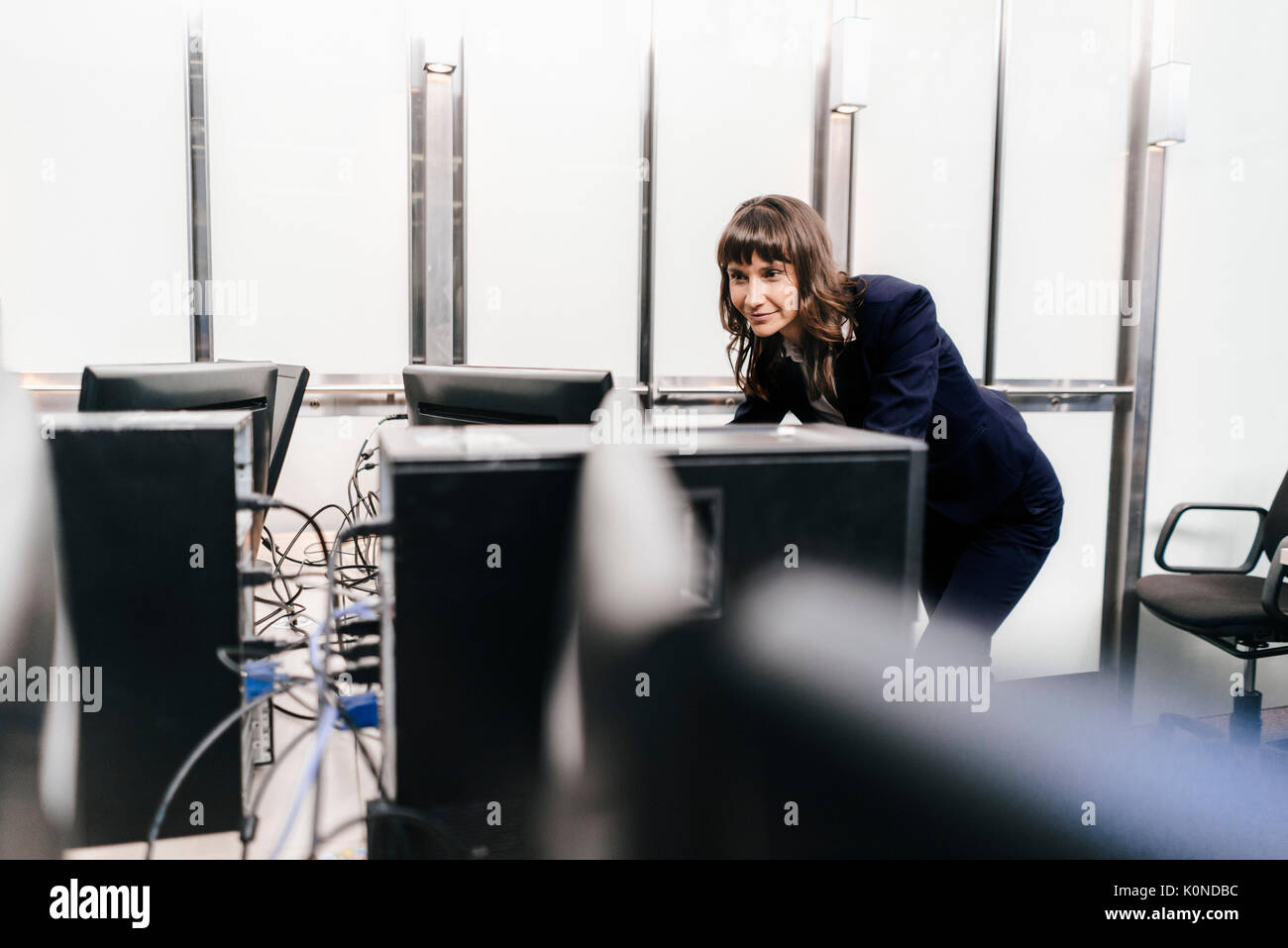 Successful businesswoman looking at monitors in office Stock Photo - Alamy