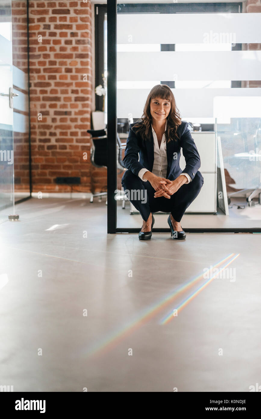 Successful businesswoman crouching in office Stock Photo - Alamy